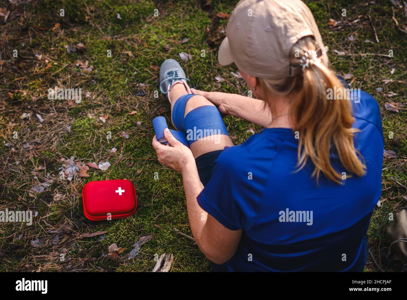 First aid after hiking accident. Injured hiker putting elastic bandage ...