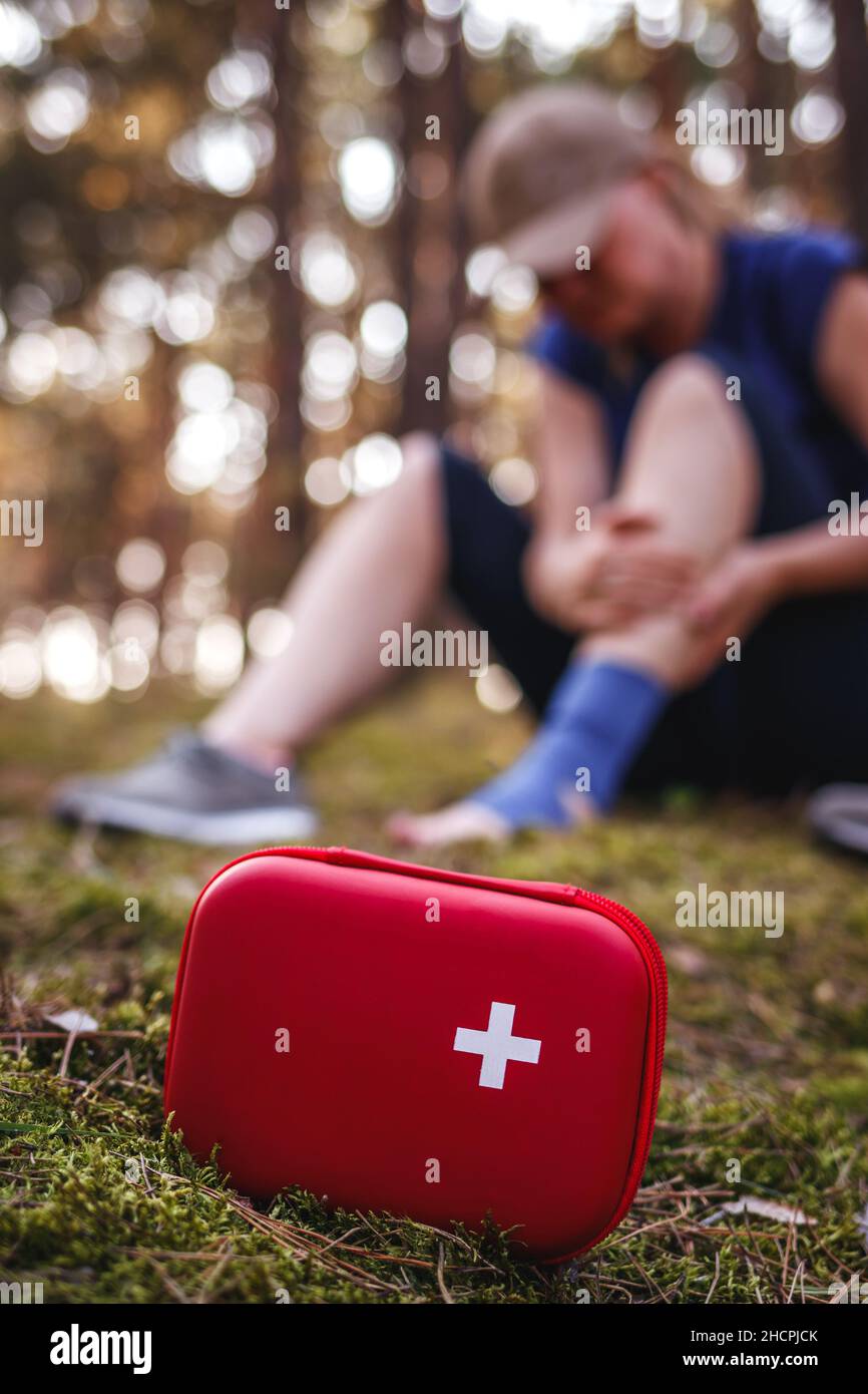 First aid kit and defocused injured tourist woman with sprain ankle in ...