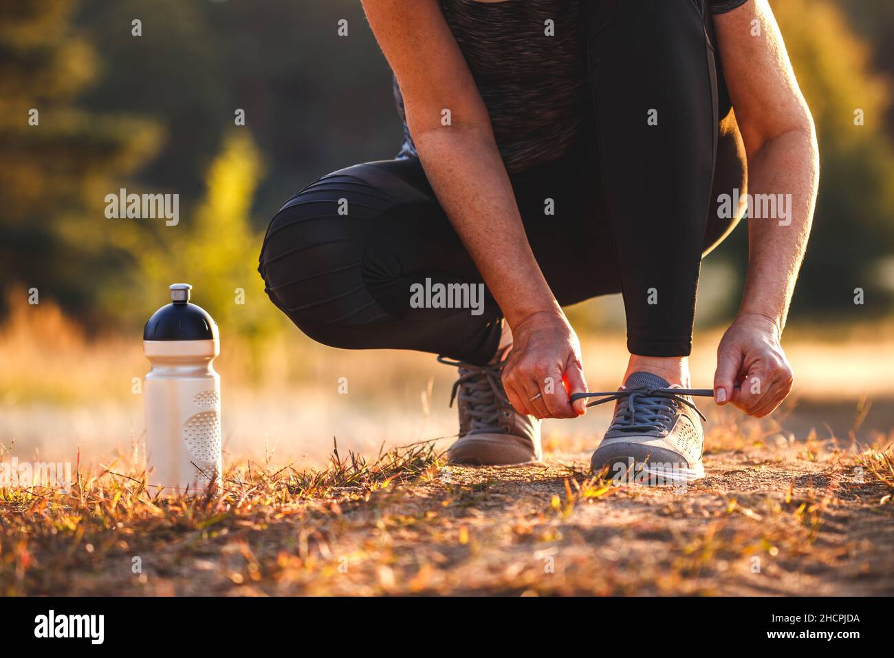 Woman tying sports shoe. Getting ready for jogging outdoors during ...