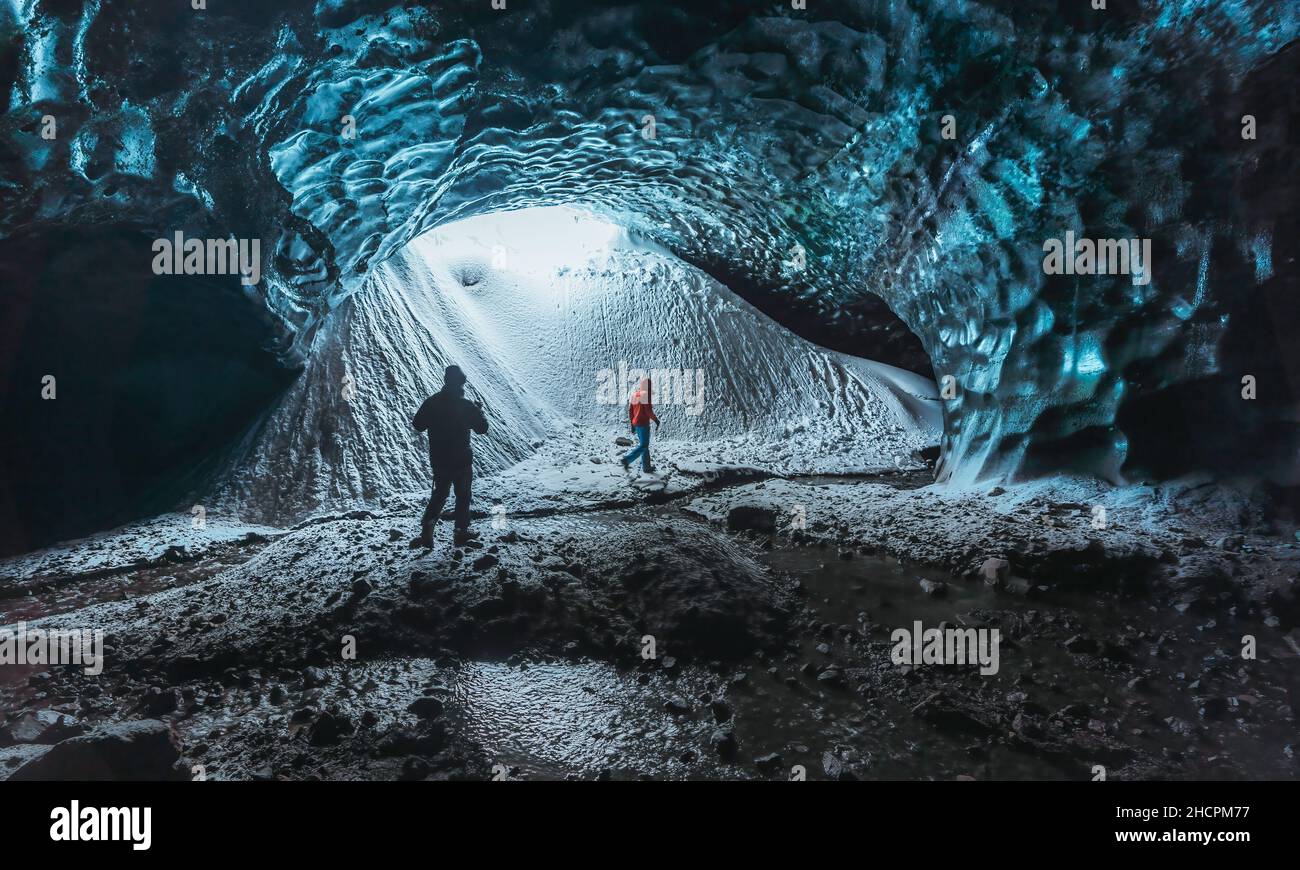 Blue crystal ice cave entrance with tourist climber and an underground ...