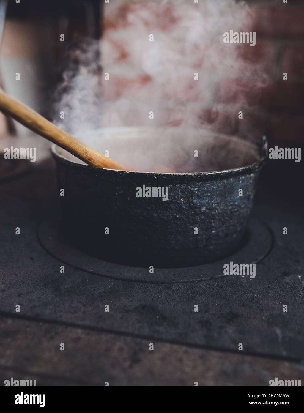 Cast iron cauldron boiling a goulash stew over a wood burning stove ...
