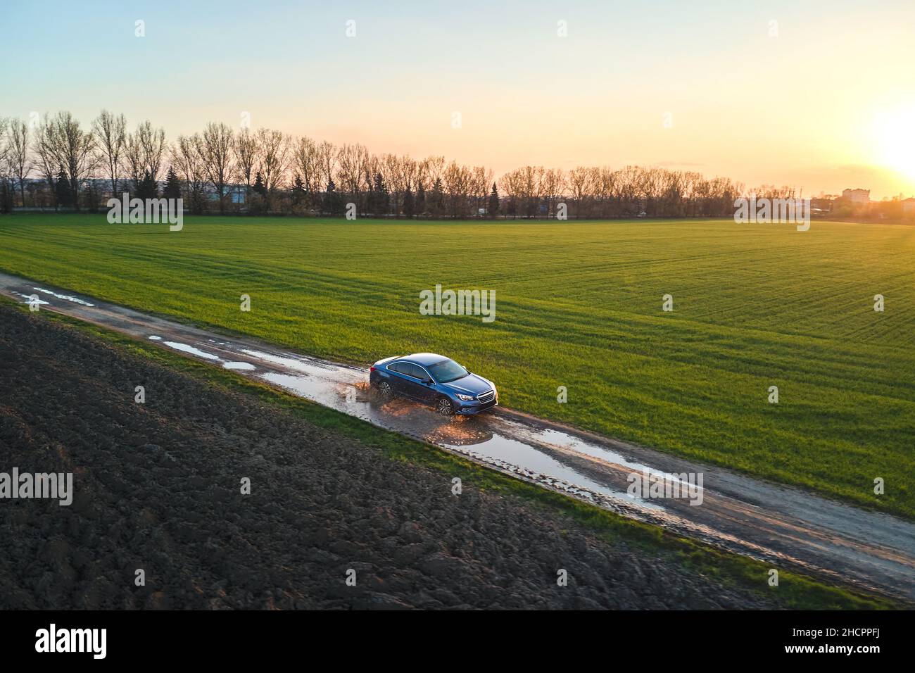 Aerial view of sedan car driving fast on dirt road at sunset. Traveling ...