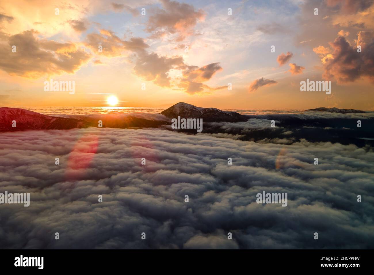 Aerial view of vibrant sunrise over white dense clouds with distant ...