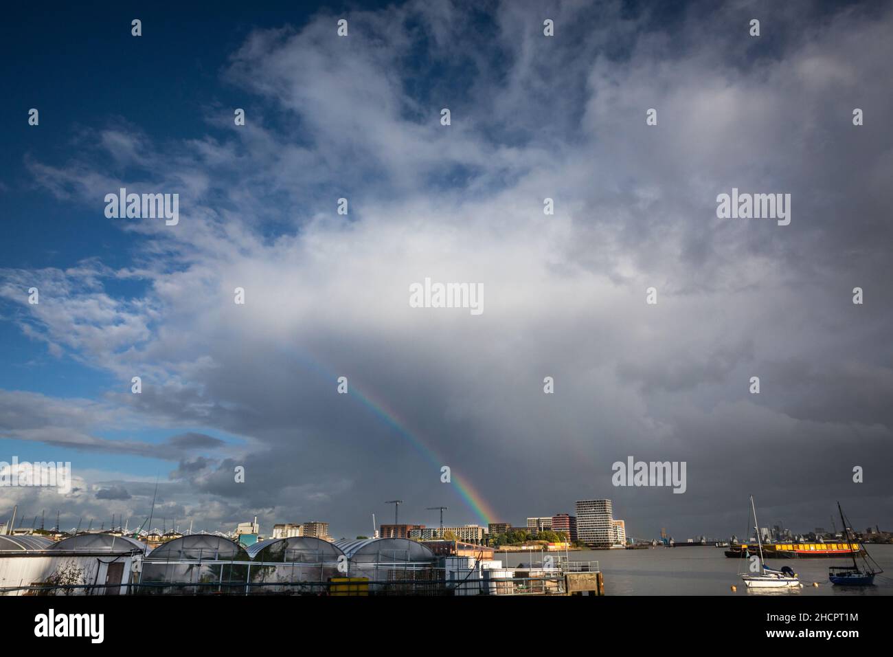 Dark clouds and rainbow over the River Thames, looking towards Leamouth ...