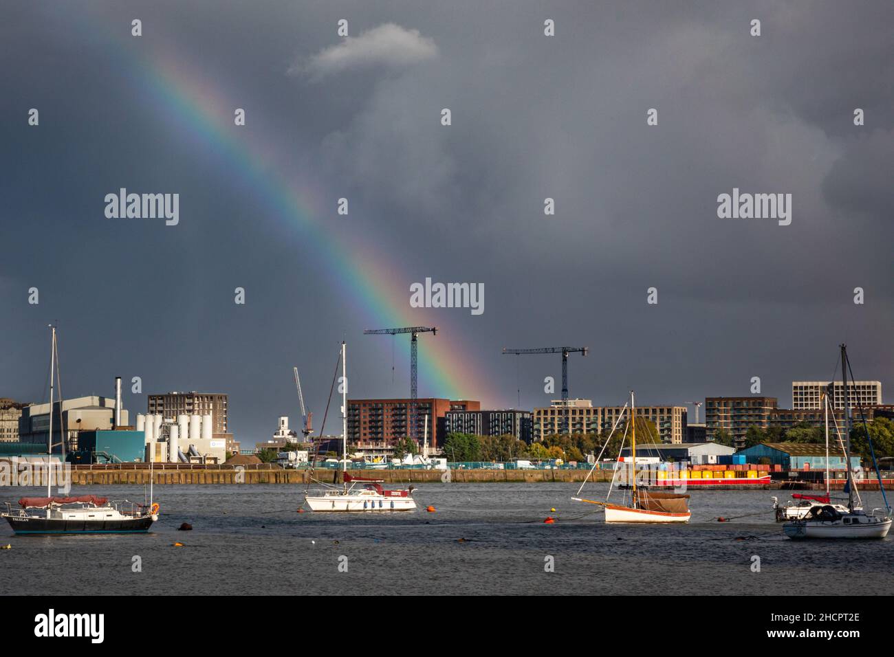 Dark rain clouds and colourful rainbow over the River Thames at ...
