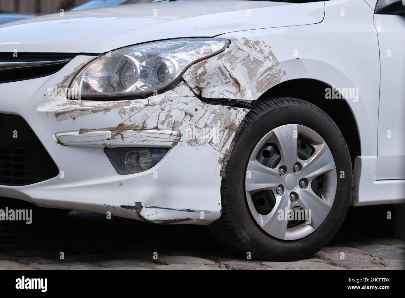 Dented car with damaged fender parked on city street side. Road safety ...