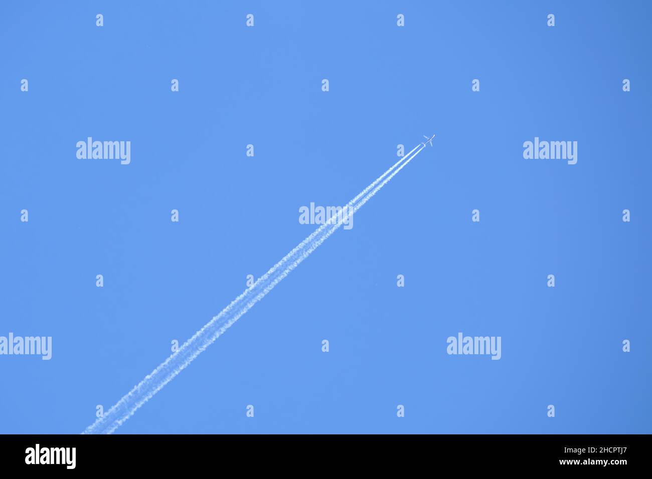 Distant passenger jet plane flying on high altitude on clear blue sky ...