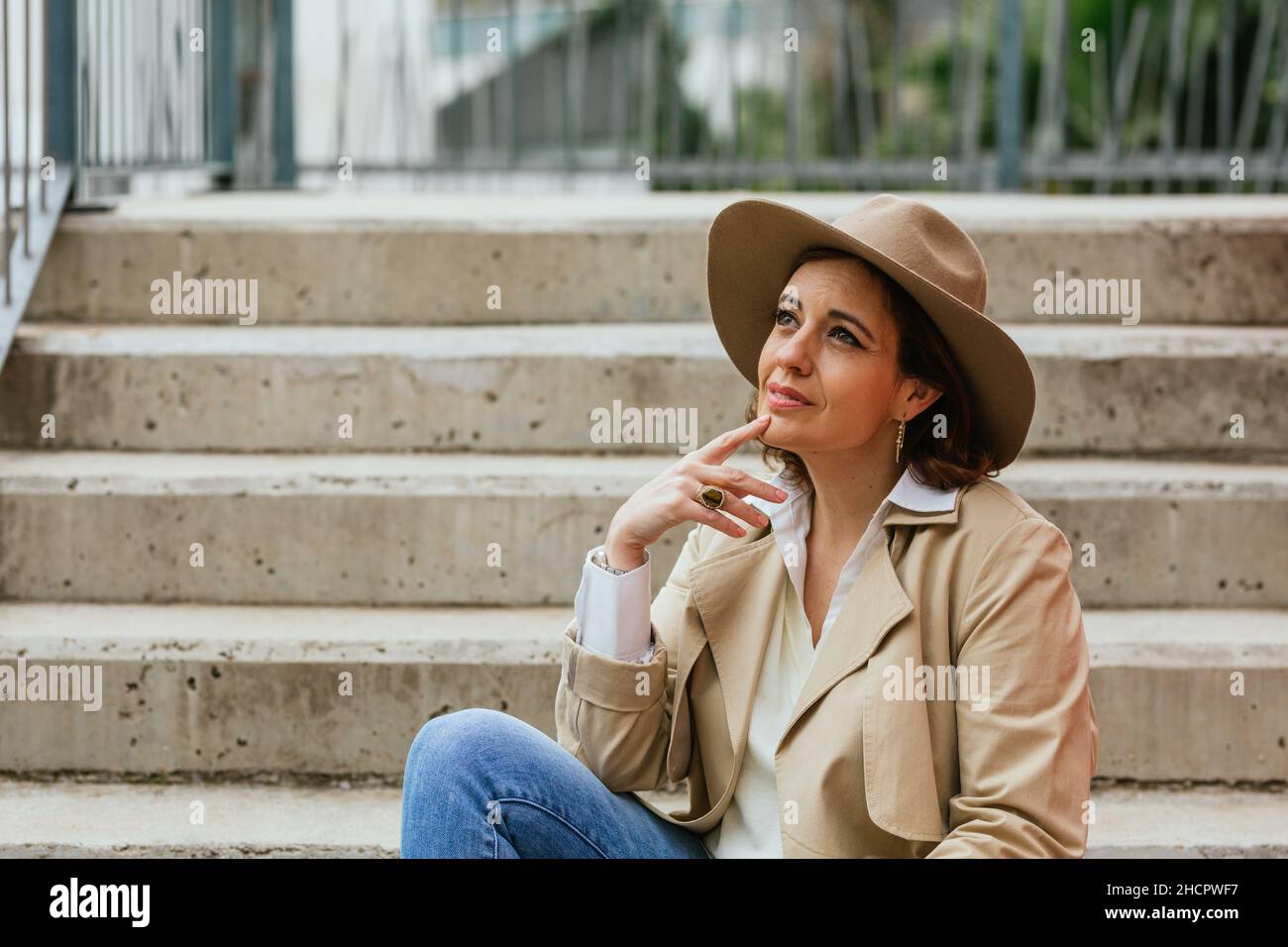 Thoughtful woman thinking about something while sitting on the stairs ...