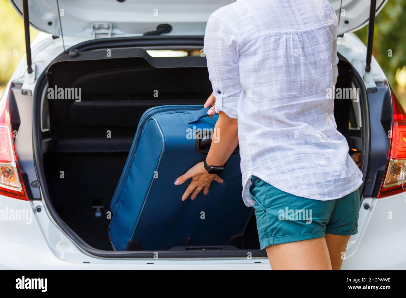 Young woman driver loading suitcase in the car trunk Stock Photo - Alamy