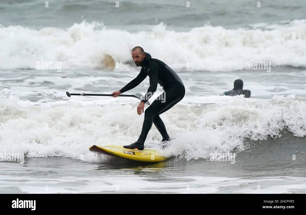A paddle boarder surfs a wave in the sea off of Bournemouth beach in ...