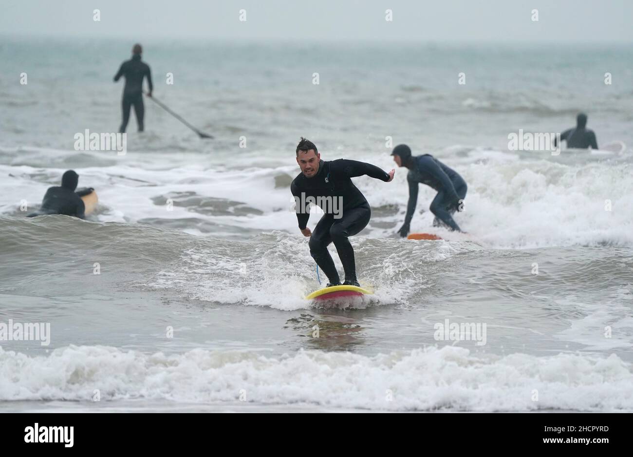 A surfer rides a wave in the sea off of Bournemouth beach in Dorset ...