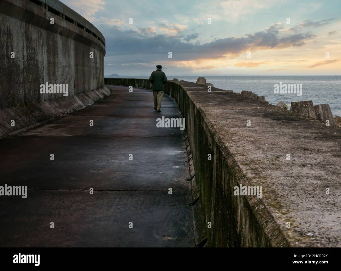 Man walking on concrete walkway of perimeter of Torness nuclear power ...