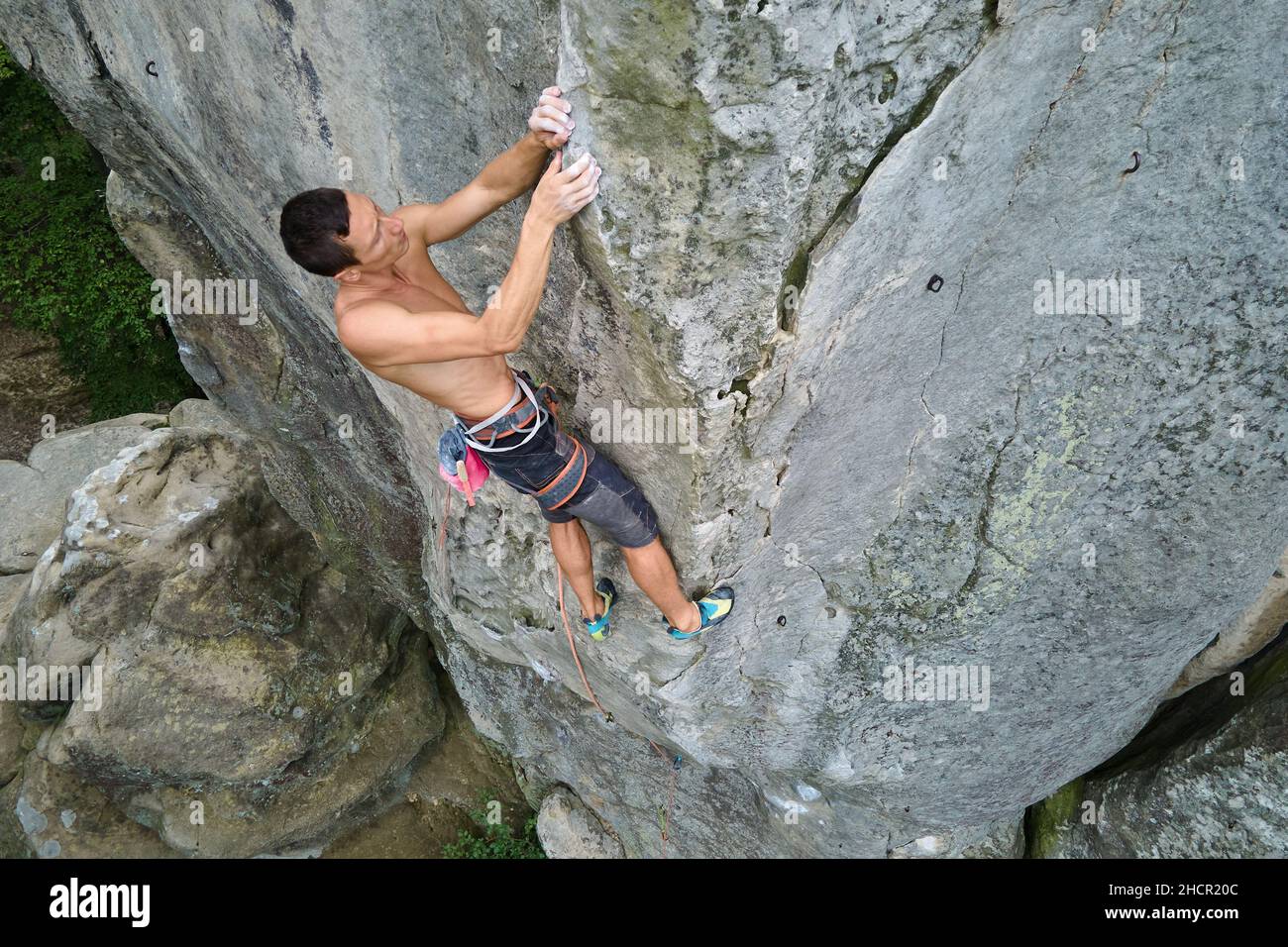 Strong male climber climbing steep wall of rocky mountain. Sportsman ...