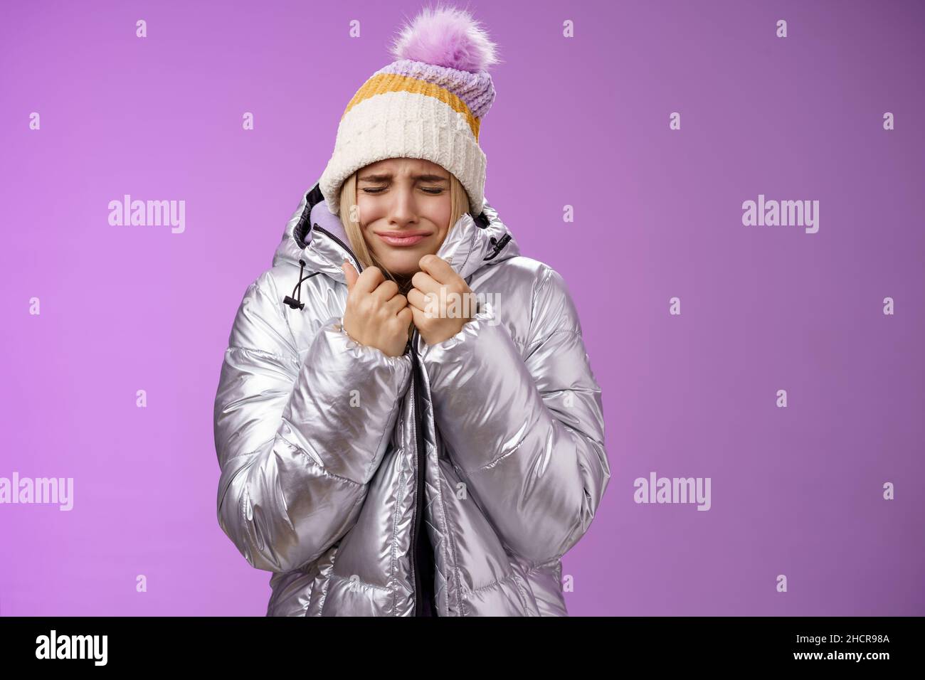 Unhappy sobbing whining cute blond girl pull jacket tight body close ...