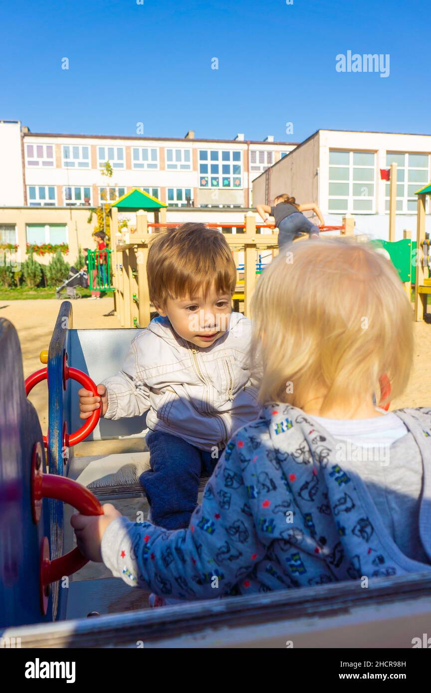 Beautiful shot of two children sitting in a car-shaped spring swing at ...