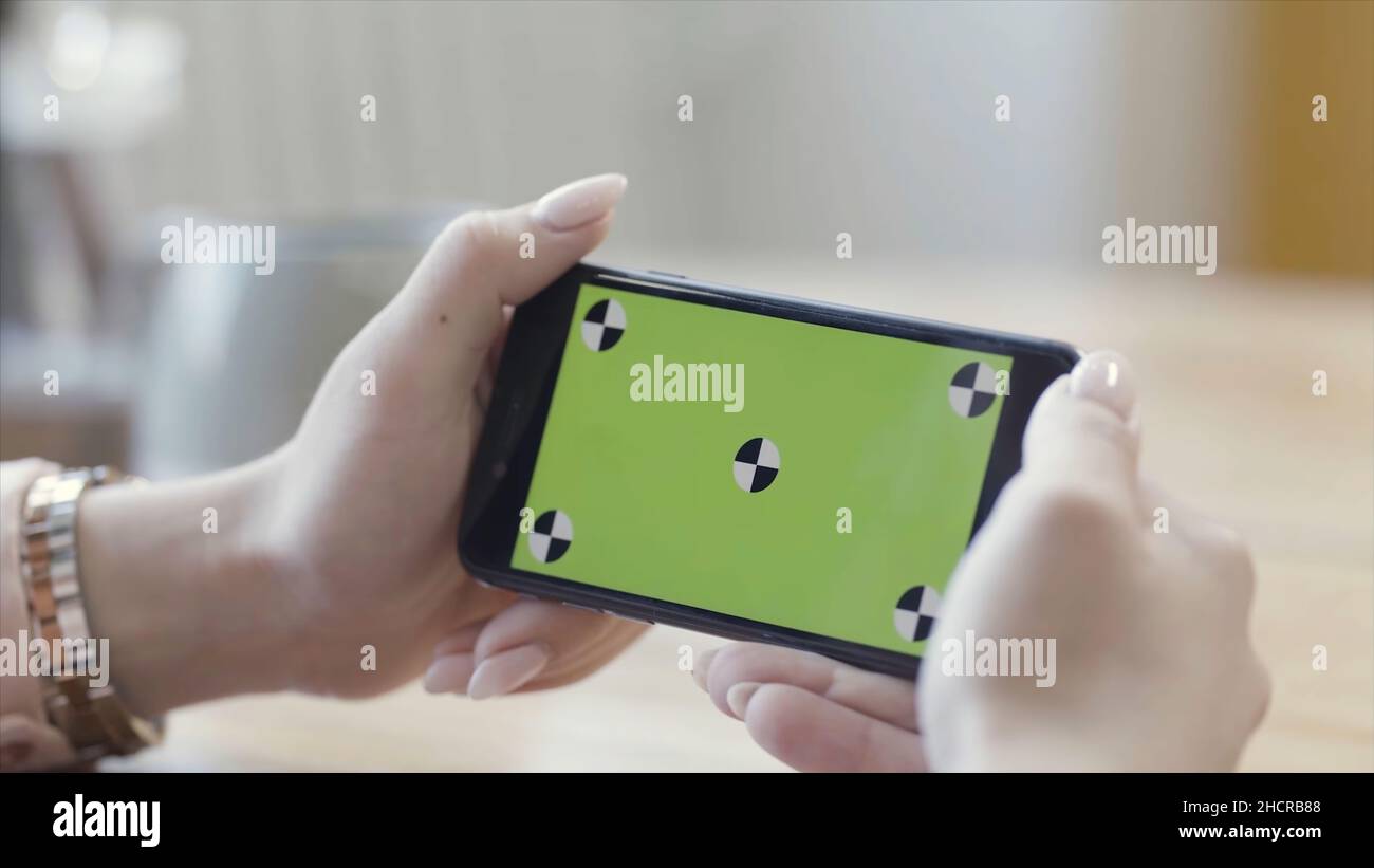 Woman looking at horizontal smartphone with green screen. Close up of ...