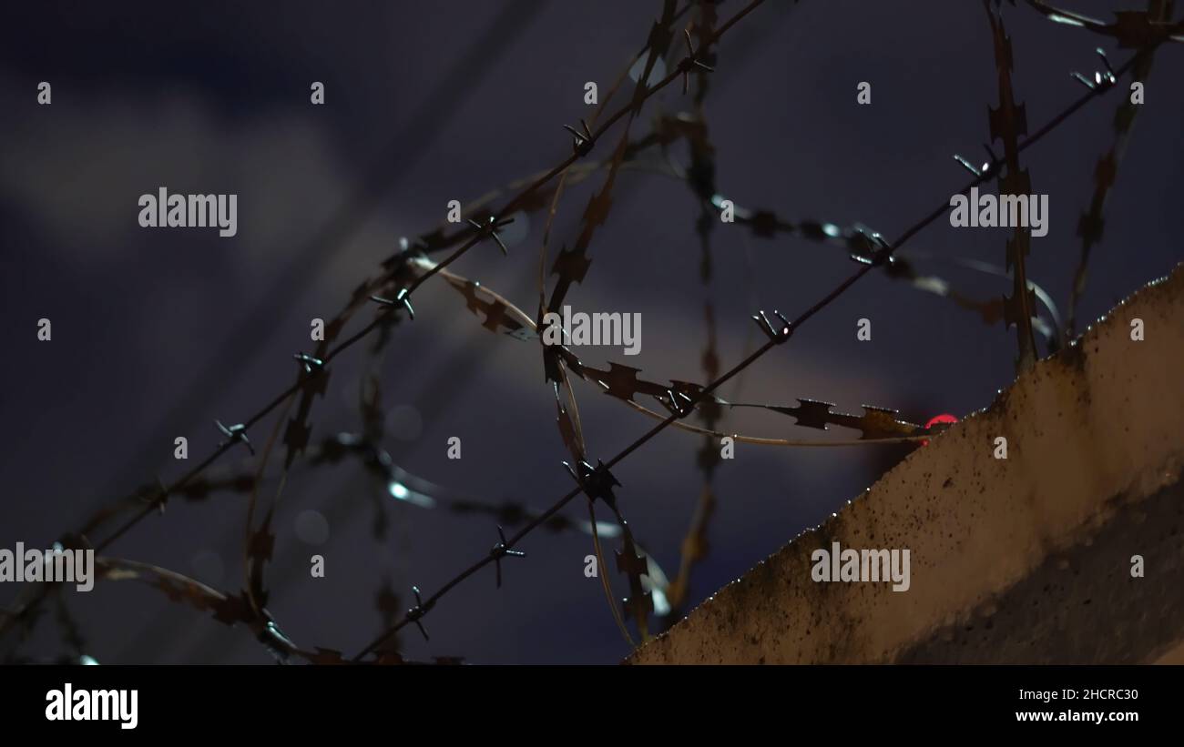 Barbed wire fence details against of the night dramatic sky. Close up ...