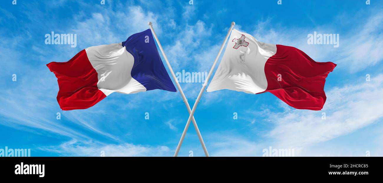 crossed national flags of France and Malta flag waving in the wind at ...