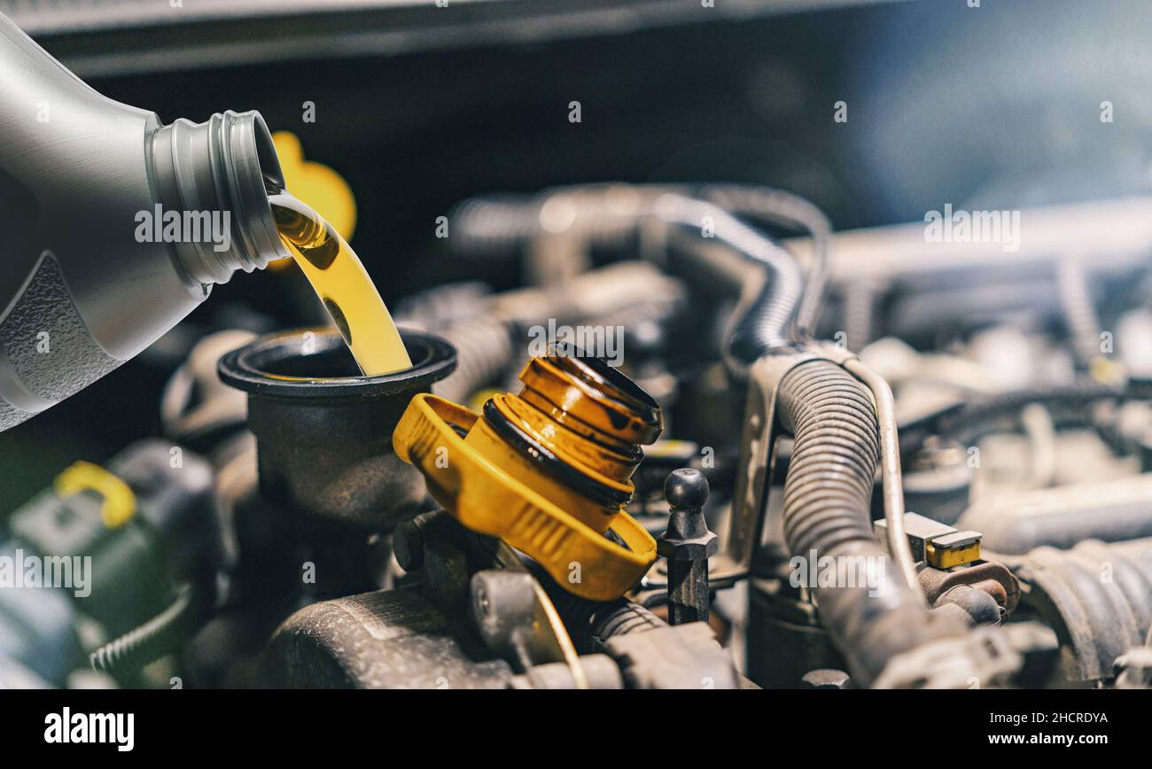 Pouring oil to car engine. Fresh oil poured during an oil change to a ...