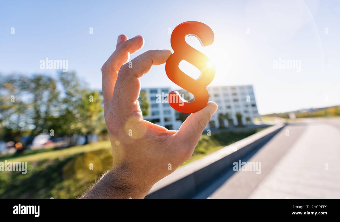 Hand holds red paragraph sign in the sun as a symbol for idea of law ...