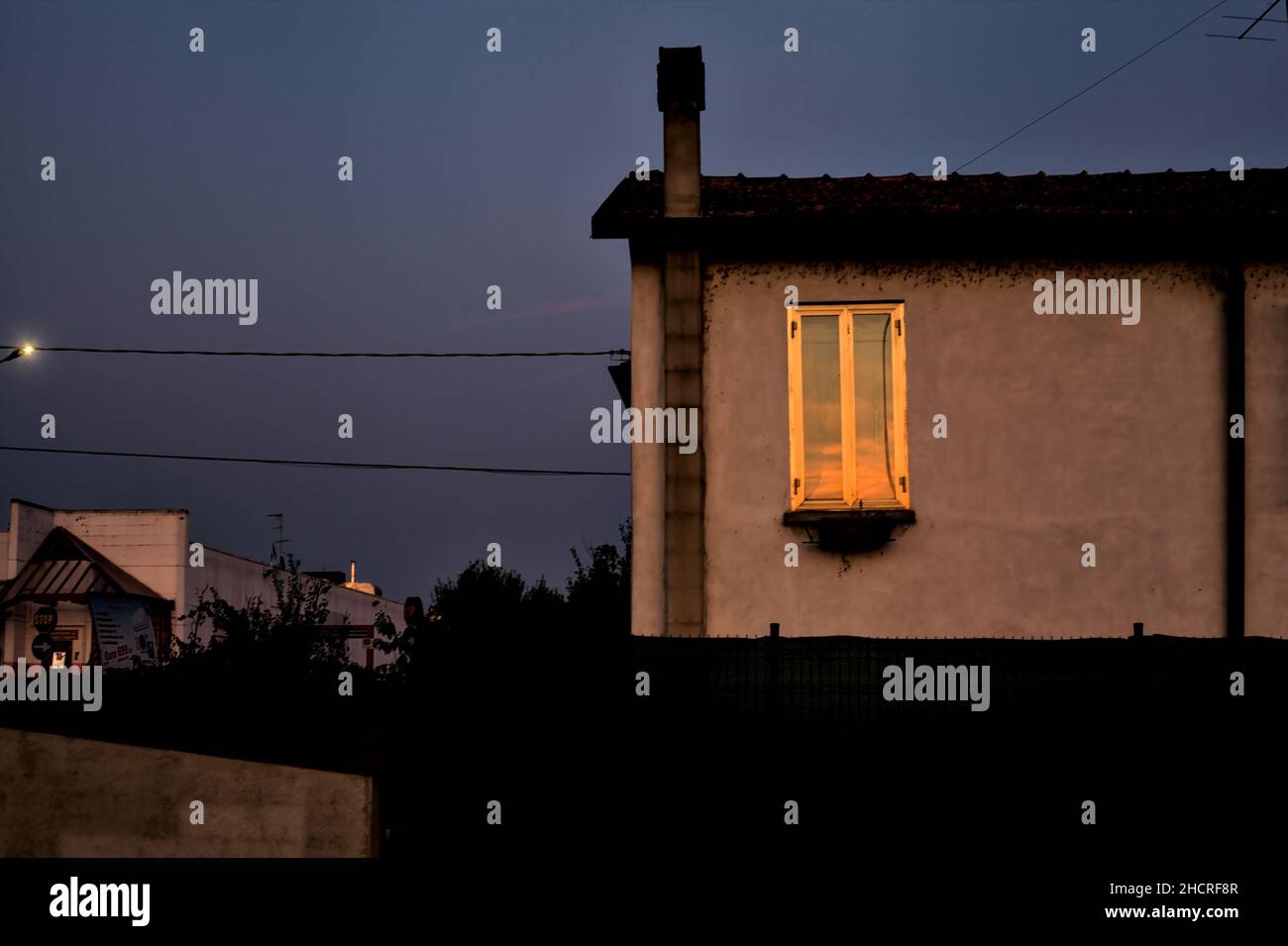 Facade of a house with a window lit by the sun at twilight Stock Photo ...