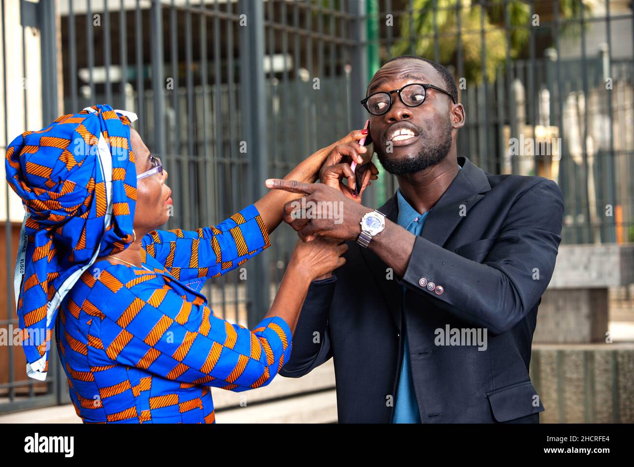 business people fighting over a phone outside. man taking his assistant ...