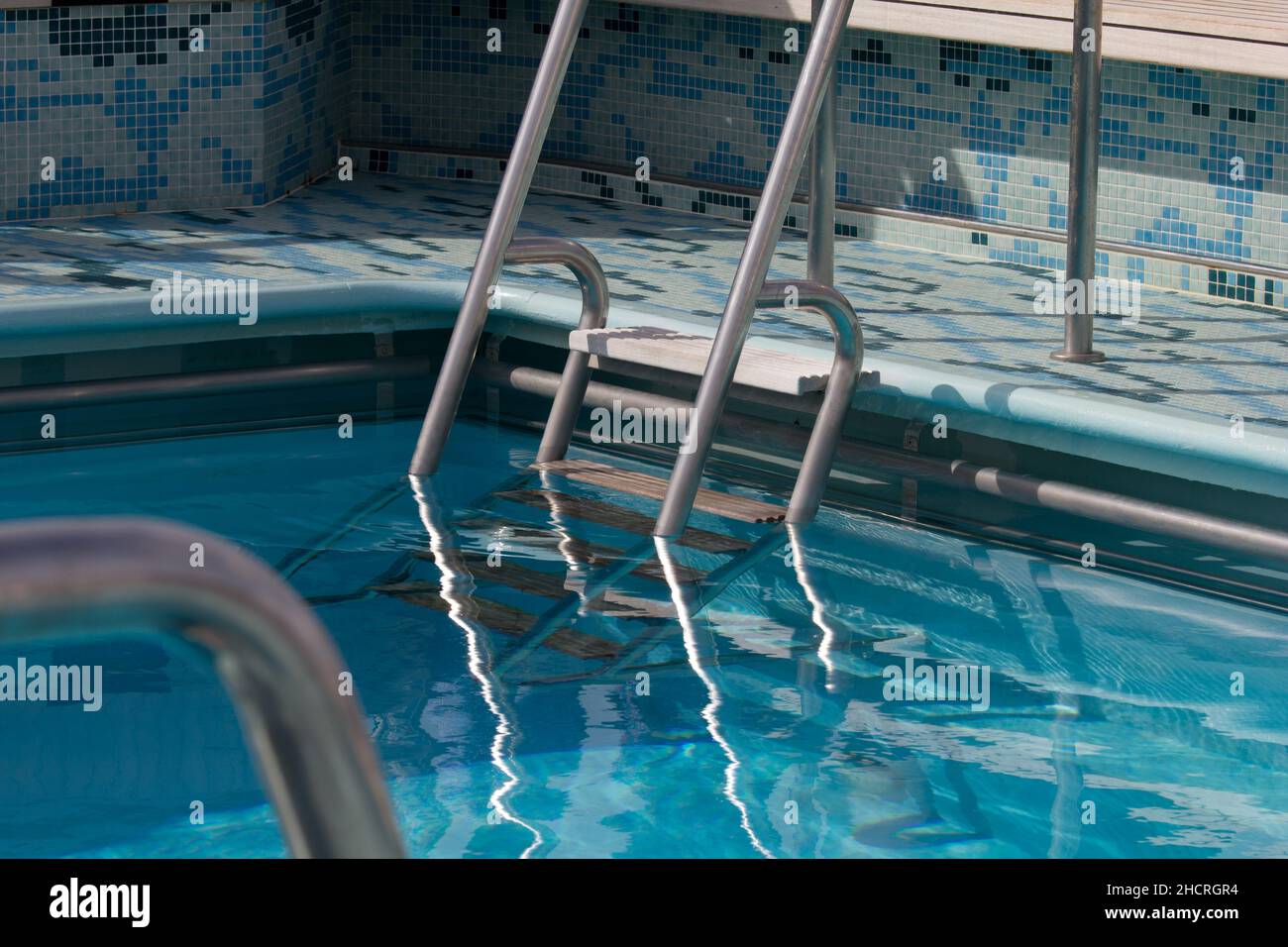 Detail of the steps and chrome hand rail of the outside swimming pool ...
