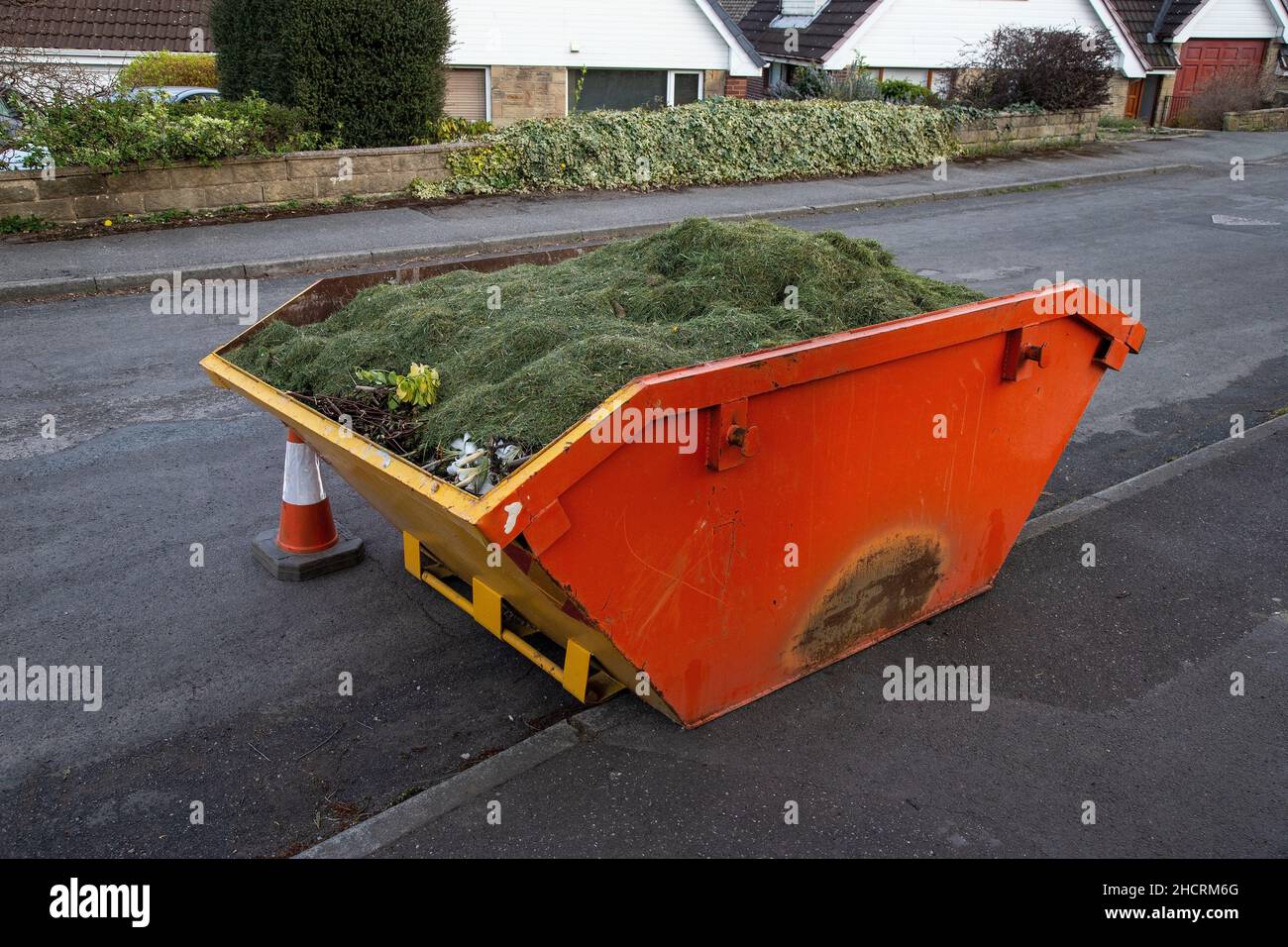 Medium sized commercial waste skip filled with garden waste outside a ...