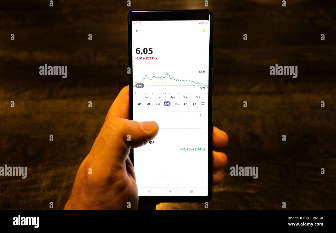 Male hand holding smartphone with mobile app. Trader analyzing stock ...