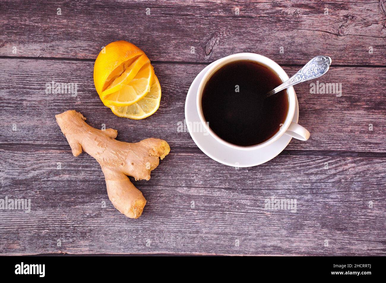 Ginger root, lemon slices and a cup of black tea on a wooden table. Top ...