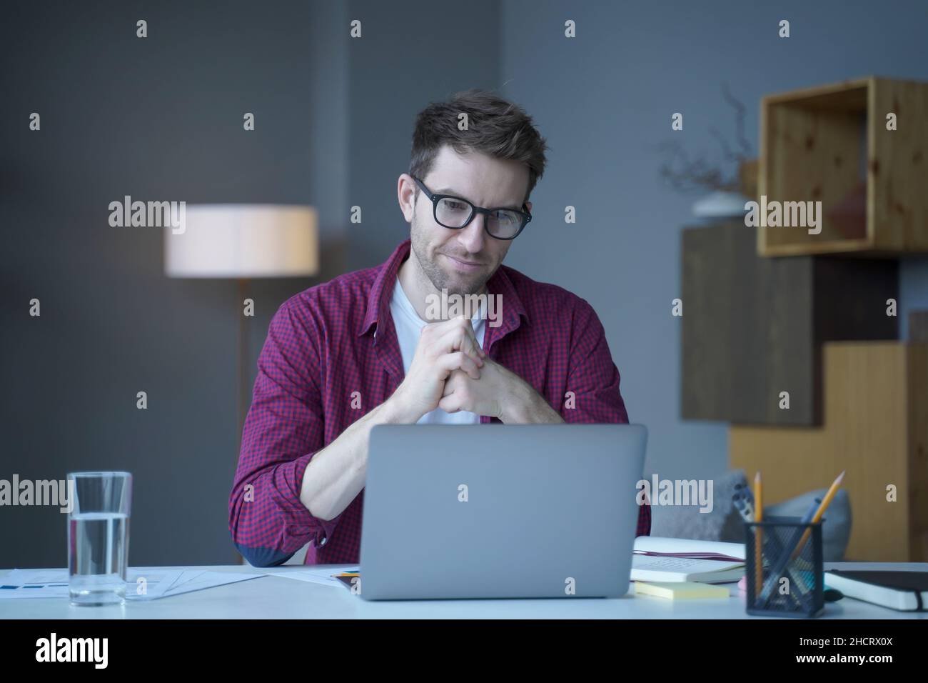 Pensive young German man home office employee sits at desk at workplace ...