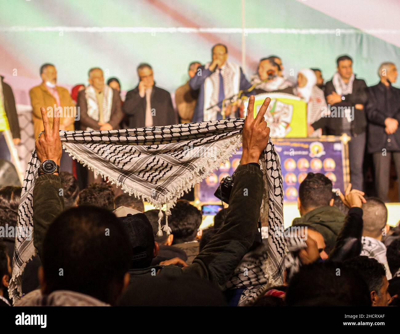 A young man raises the Palestinian keffiyeh during a rally to ...
