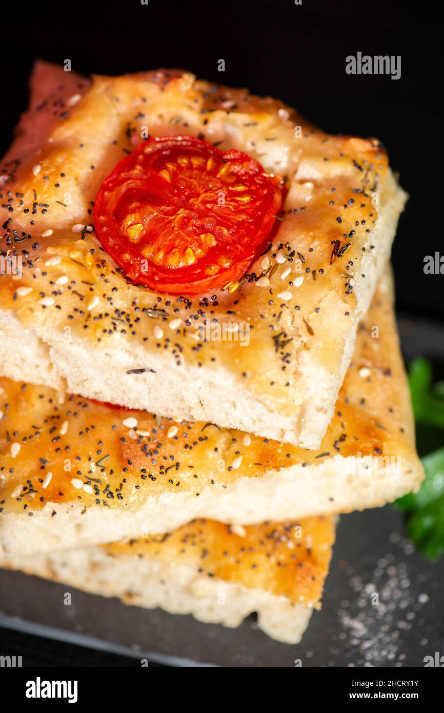 Fresh baked focaccia with cherry tomato, poppy and sesame seeds, pepper ...