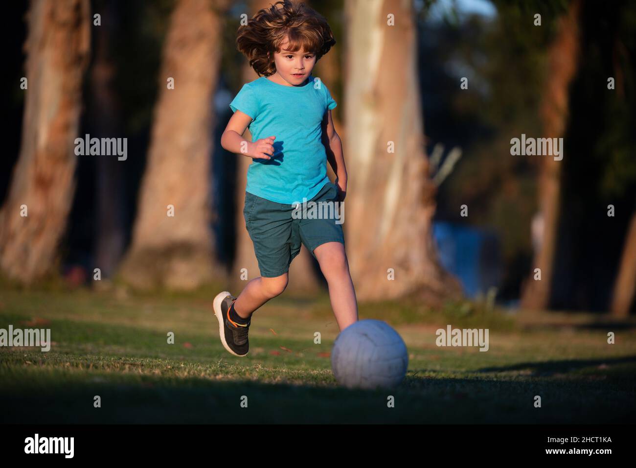 Boy child playing football on football field. Kid playing soccer. Young ...