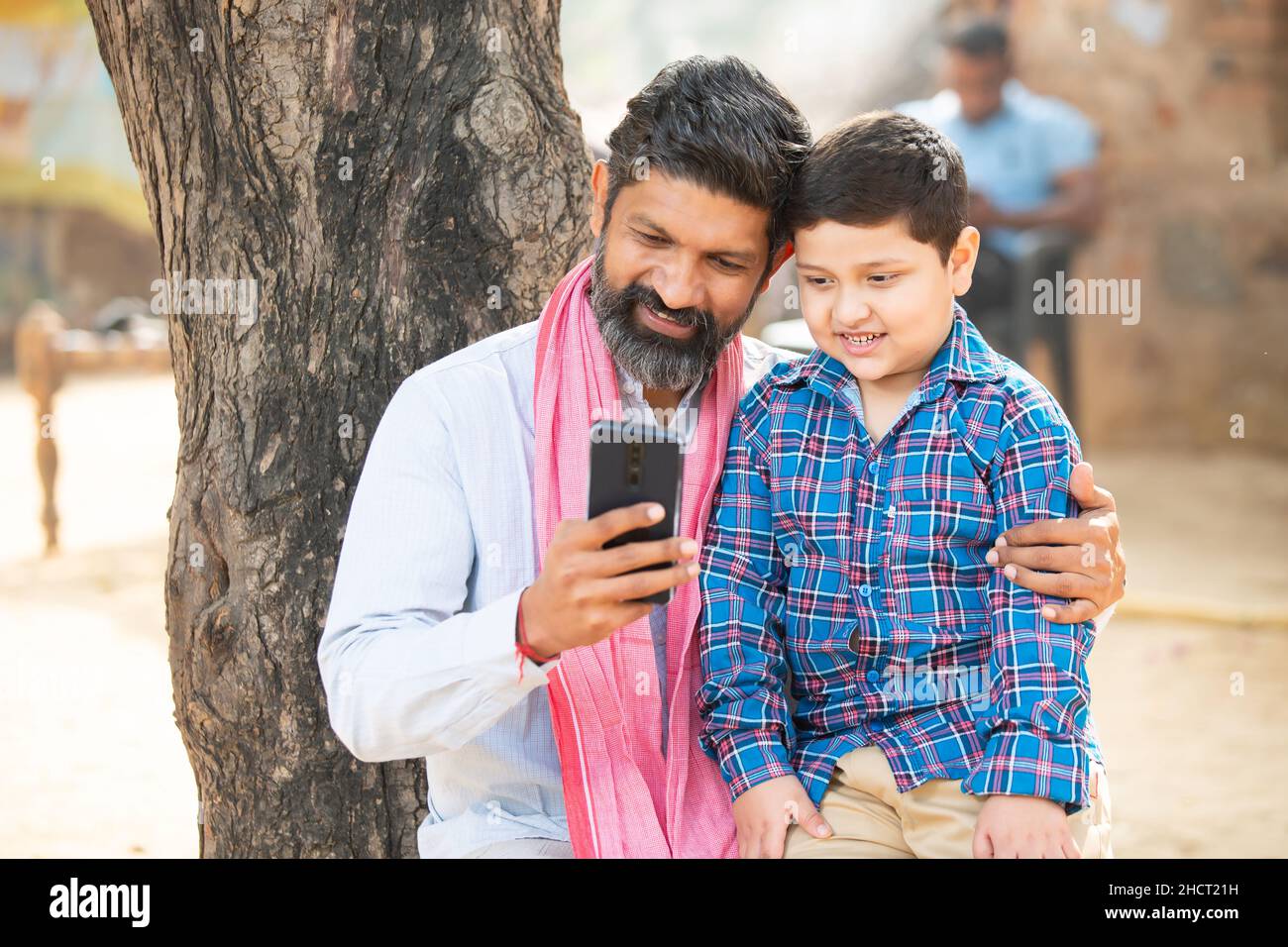 Happy Indian father using smart phone while sitting with his cute ...