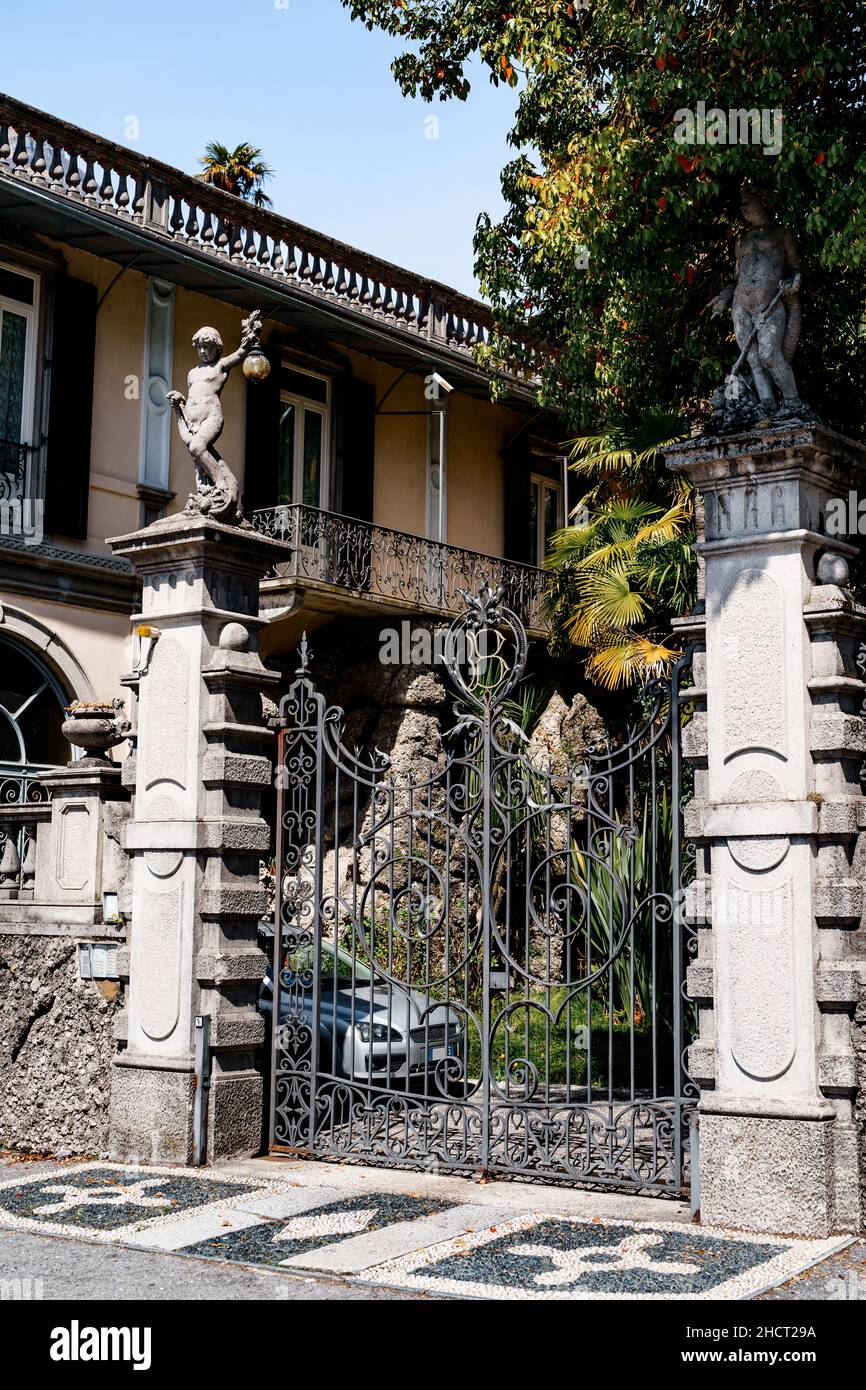 Monogrammed wrought-iron gate surrounded by columns with statues Stock ...