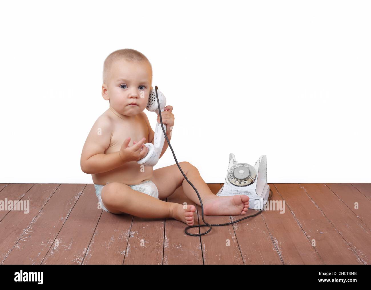 Portrait of the little boy speaking by vintage phone on a wooden, white ...