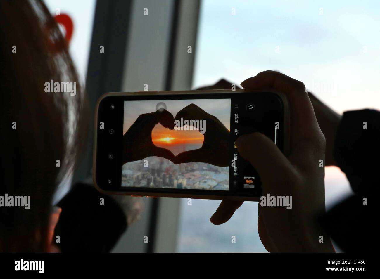 Shanghai. 1st Jan, 2022. A visitor poses for photos with sunrise at the ...