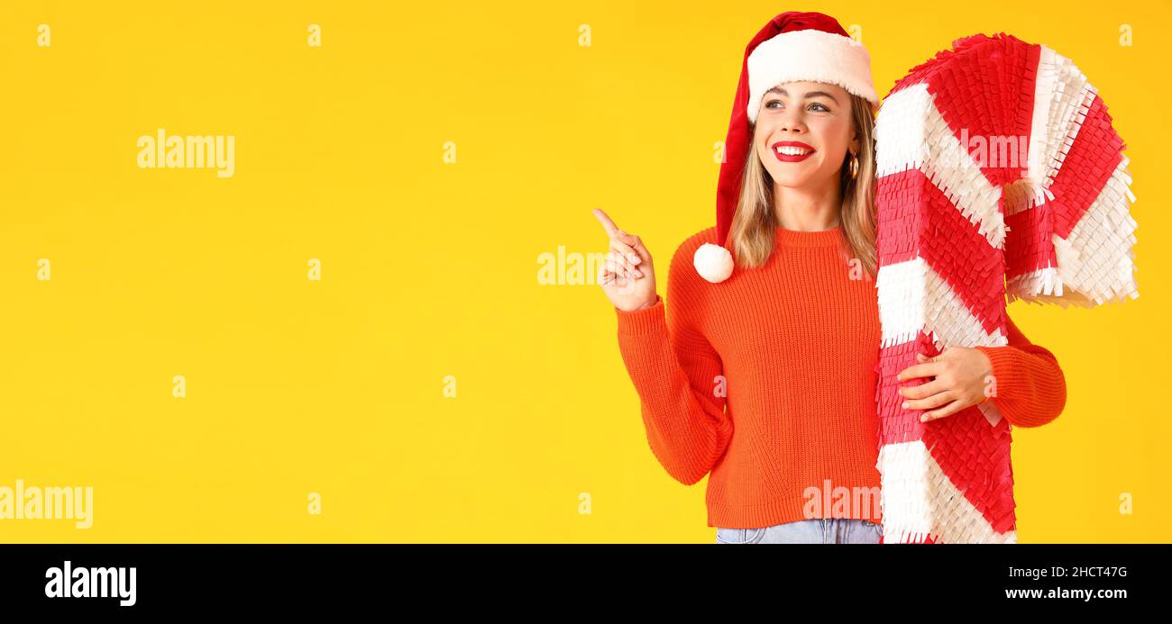 Beautiful young woman with candy cane pinata pointing at something on ...