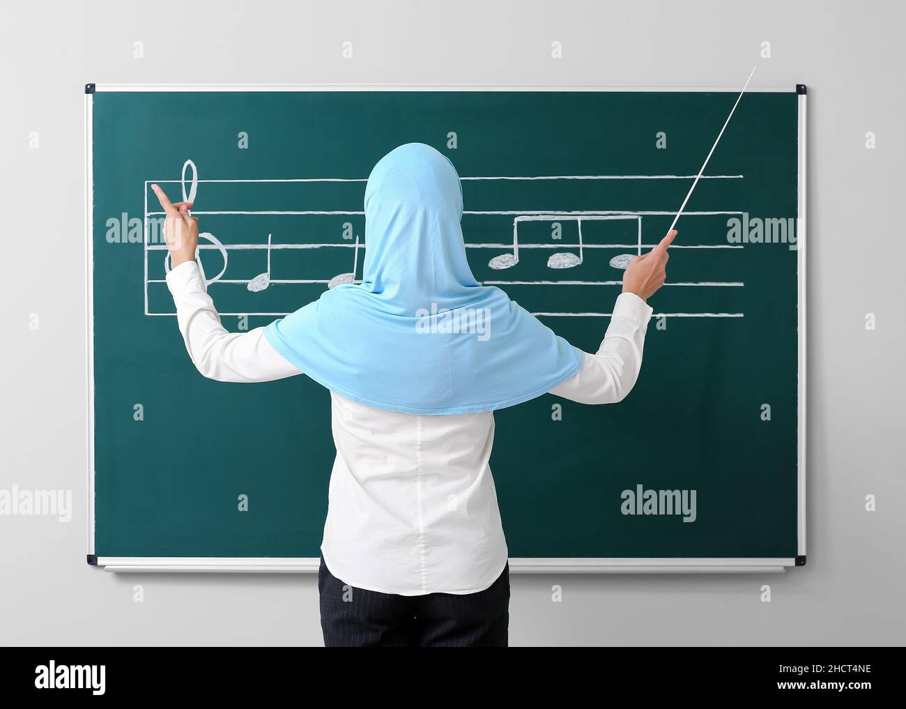 Muslim music teacher near blackboard in classroom Stock Photo - Alamy