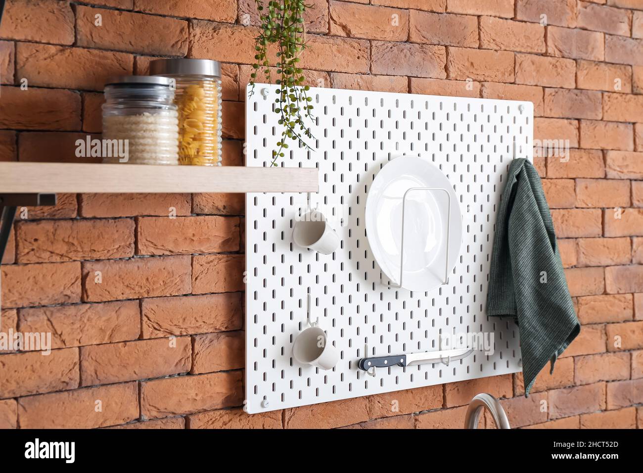 Peg board with kitchenware hanging on brick wall Stock Photo - Alamy