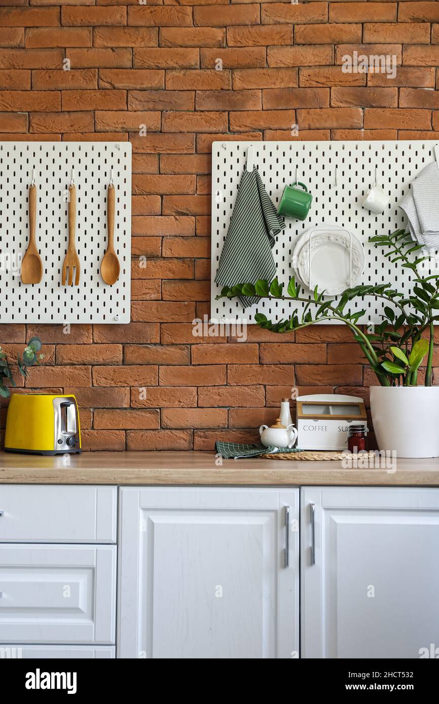 Peg boards with kitchenware hanging on brick wall Stock Photo - Alamy
