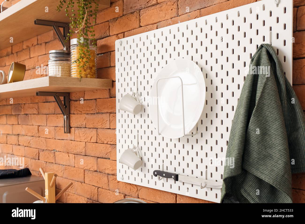 Peg board with kitchenware hanging on brick wall Stock Photo - Alamy