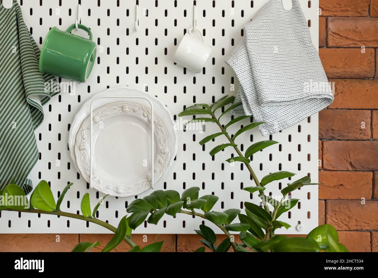 Peg board with kitchenware hanging on brick wall Stock Photo - Alamy