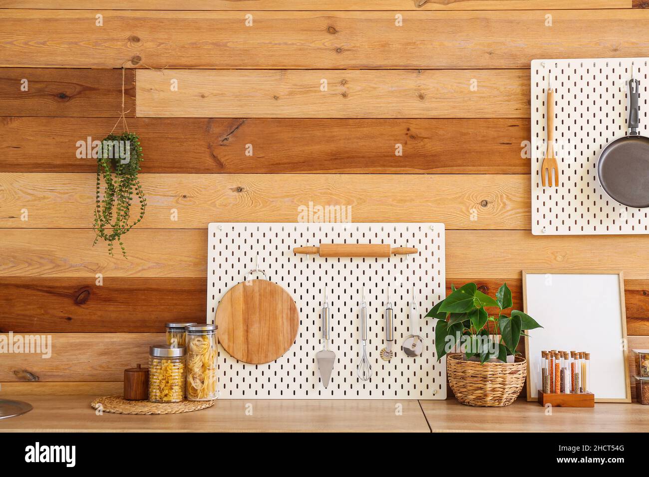 Peg board with kitchenware on kitchen counter near wooden wall Stock ...