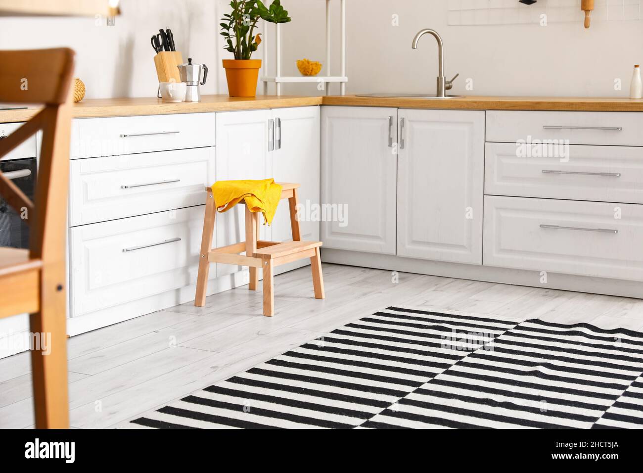 Interior of light kitchen with white counters and wooden step stool ...
