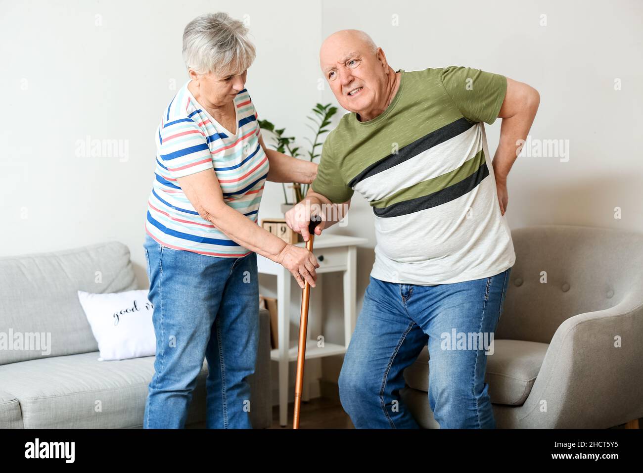 Senior woman helping her husband with back pain at home Stock Photo - Alamy