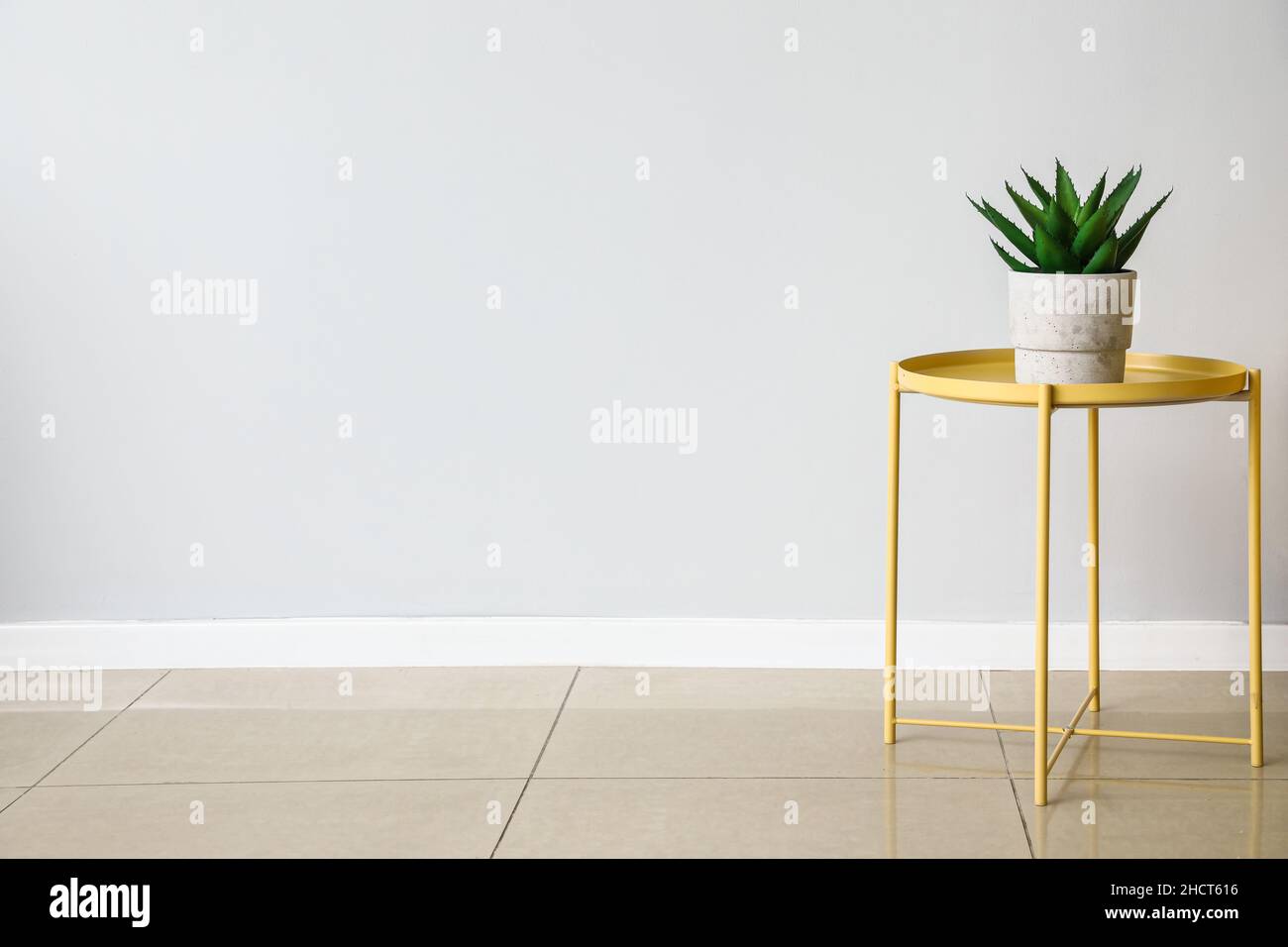 Yellow coffee table with houseplant near light wall Stock Photo - Alamy