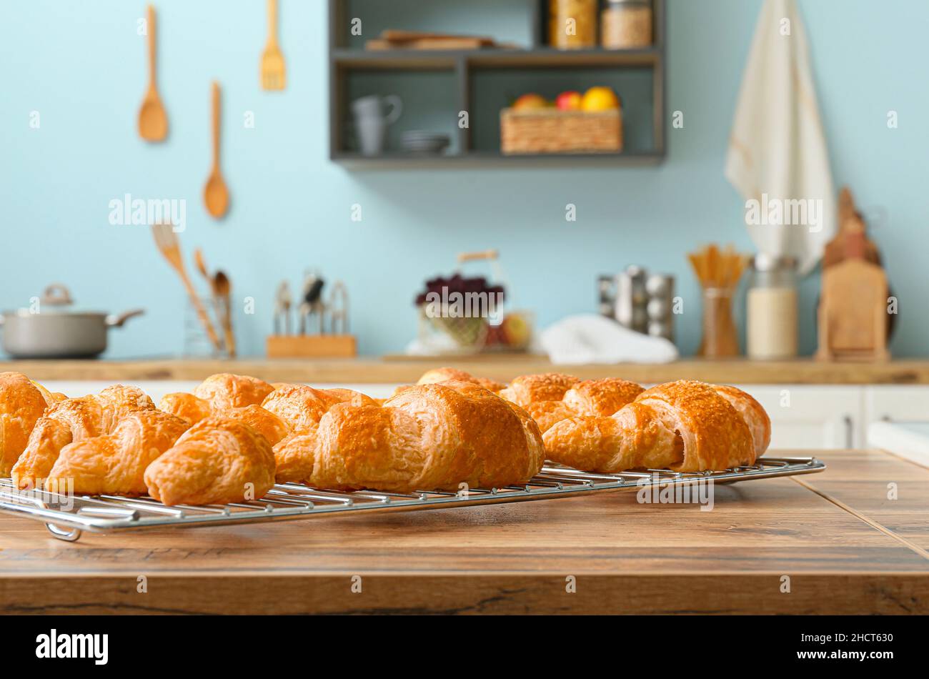 Baking grid with croissants on wooden table top in kitchen Stock Photo ...
