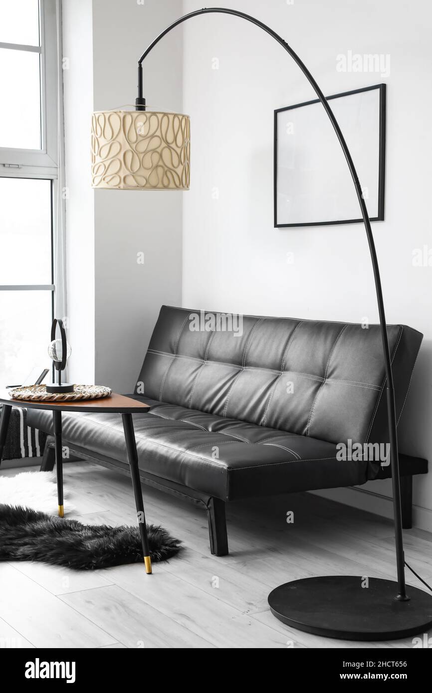 Interior of light living room with black couch, table and lamps Stock ...